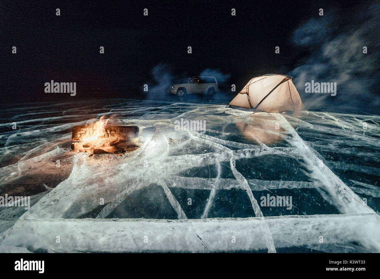 Fire on ice at night. Campground on ice. Tent stands next to bonfire ...