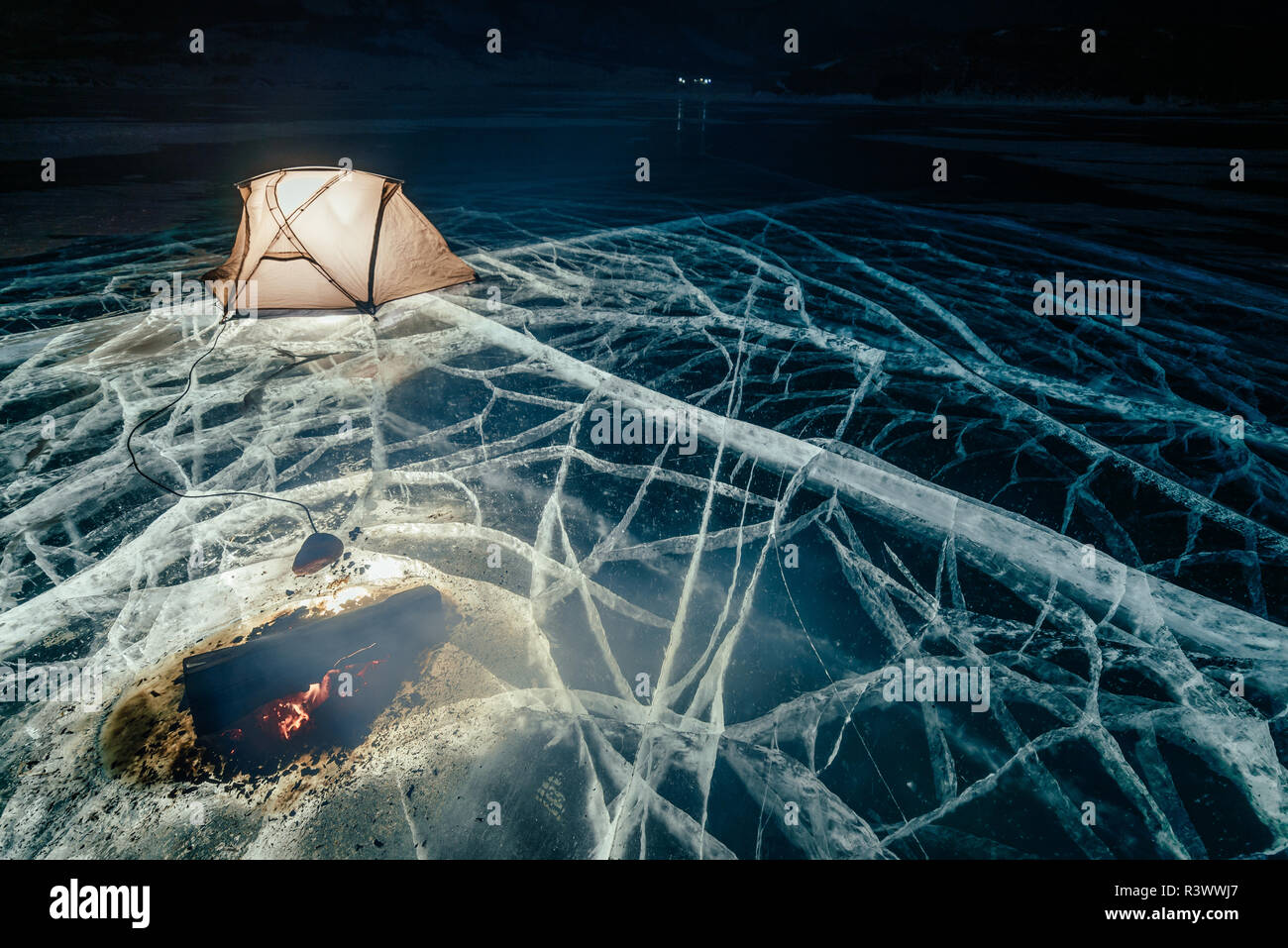 Fire on ice at night. Campground on ice. Tent stands next to bonfire ...