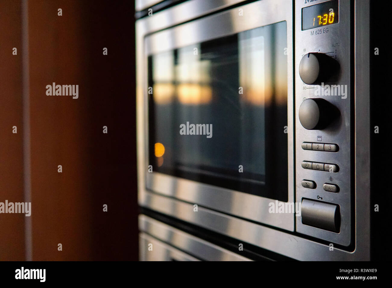 evening sun reflicting of stainless steel microwave oven door closeup ...