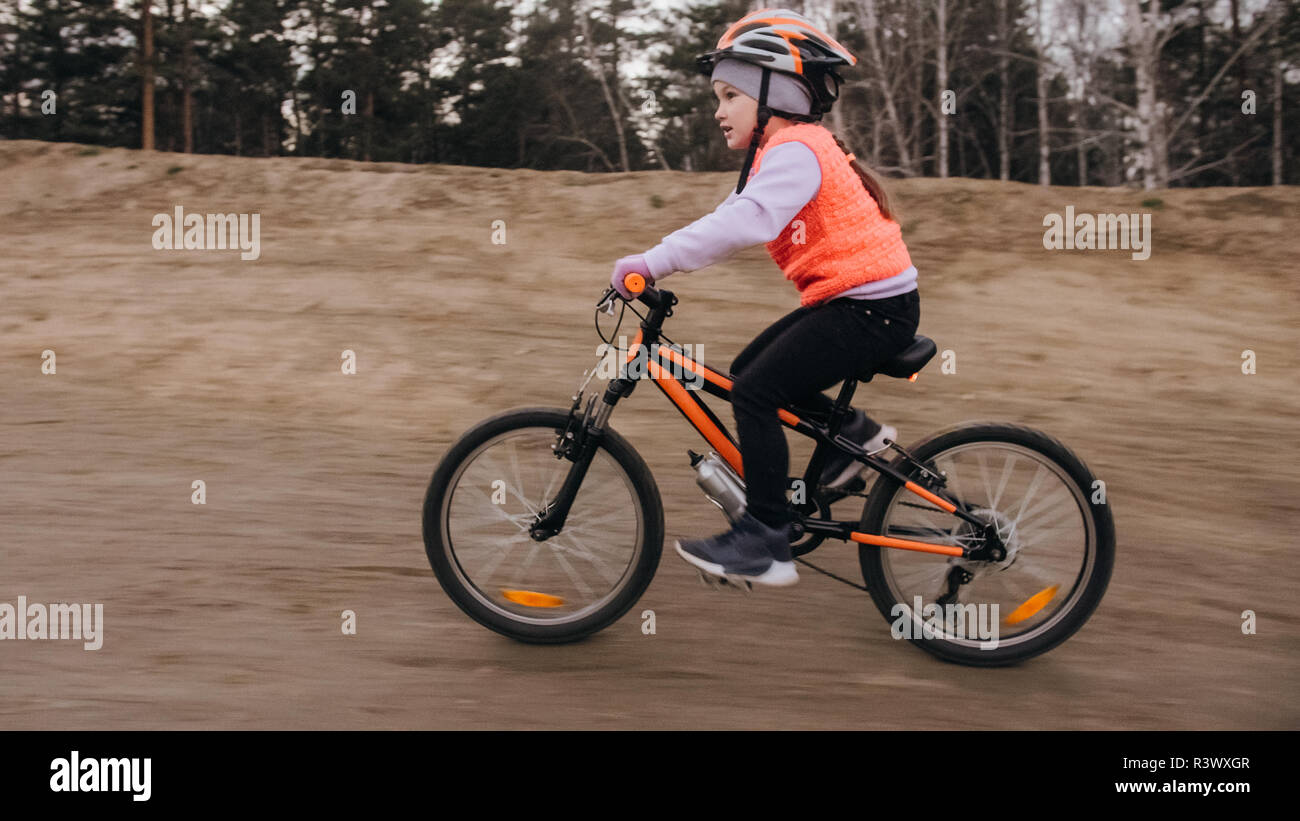 One caucasian children rides bike road track in dirt park. Girl riding ...