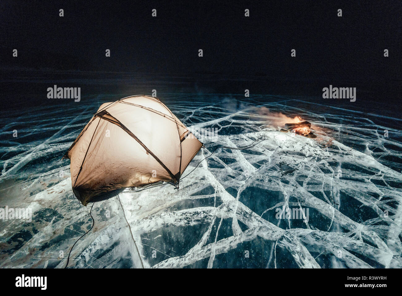 Fire on ice at night. Campground on ice. Tent stands next to bonfire ...