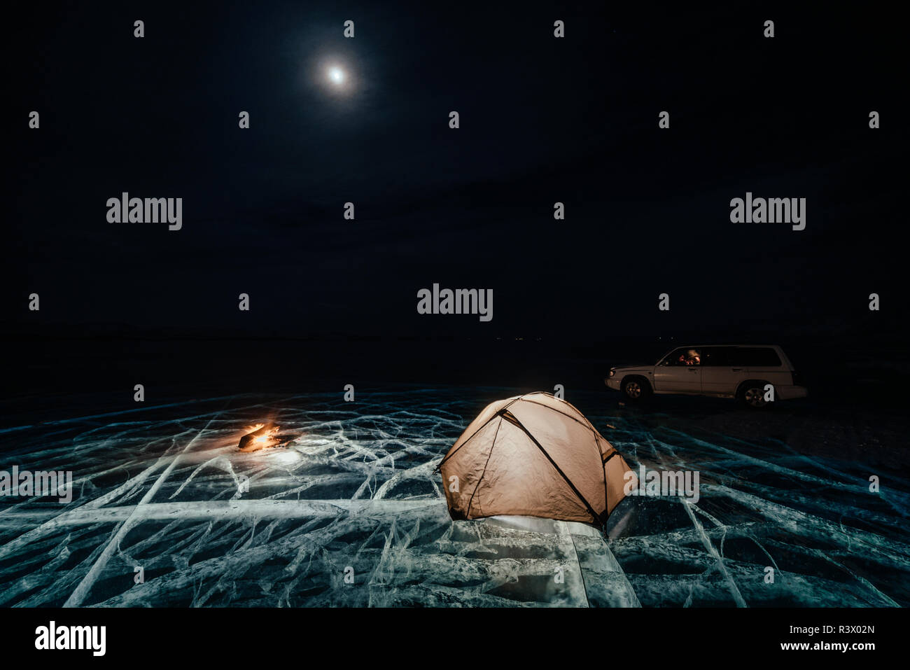 Fire on ice at night. Campground on ice. Tent stands next to bonfire ...