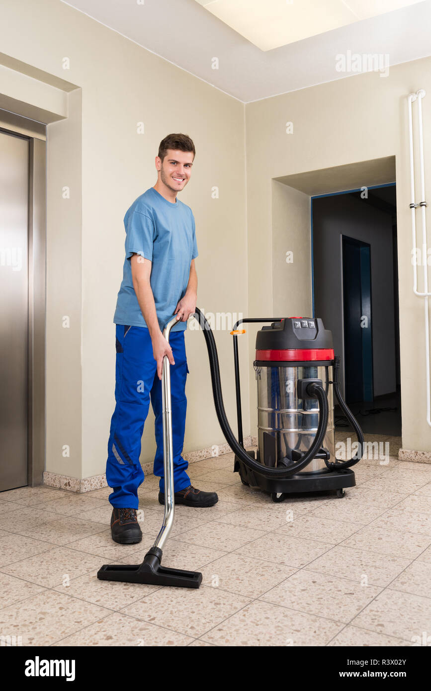 Male Worker Cleaning With Vacuum Cleaner Stock Photo - Alamy