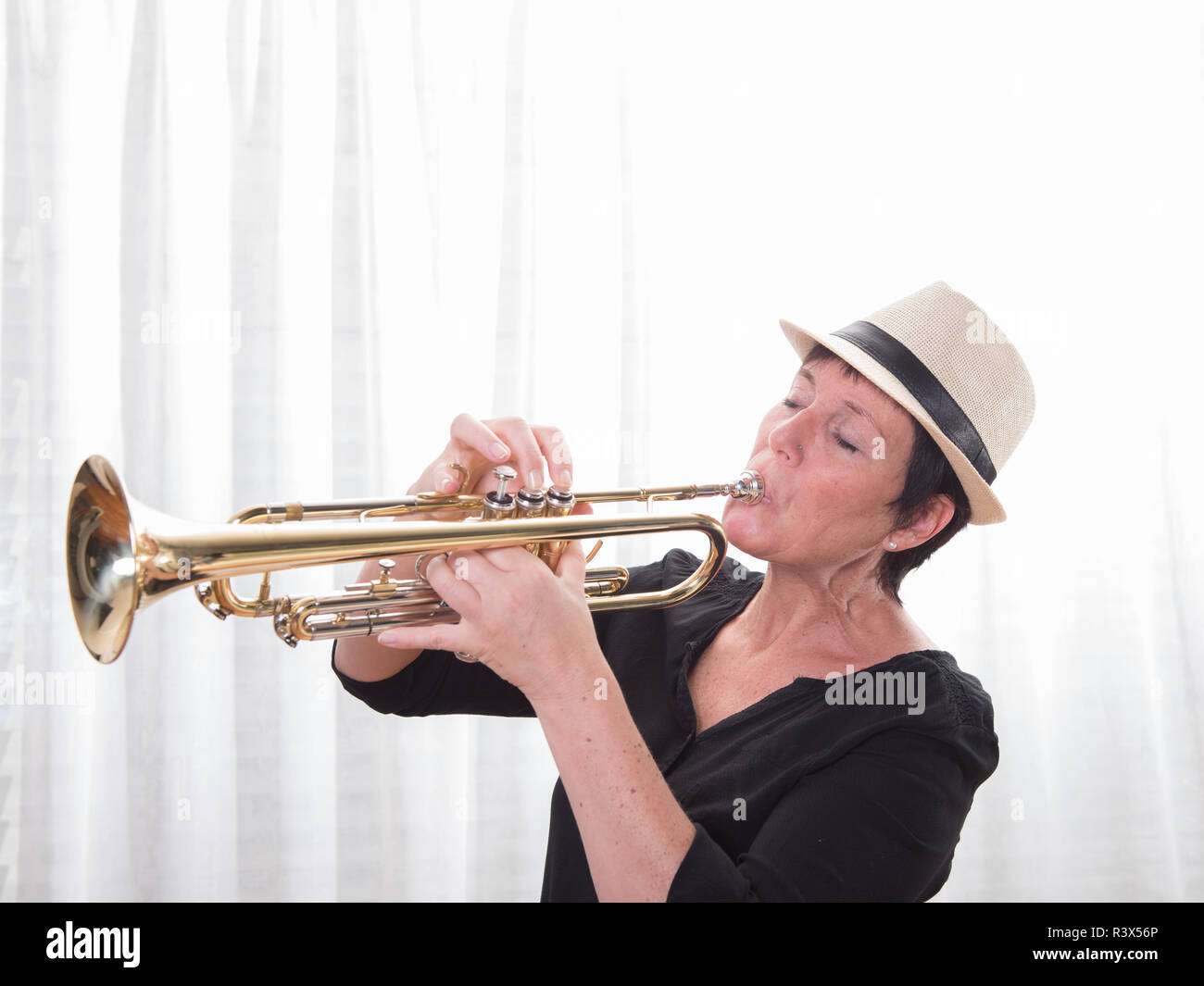 attractive woman with hat playing the trumpet Stock Photo - Alamy