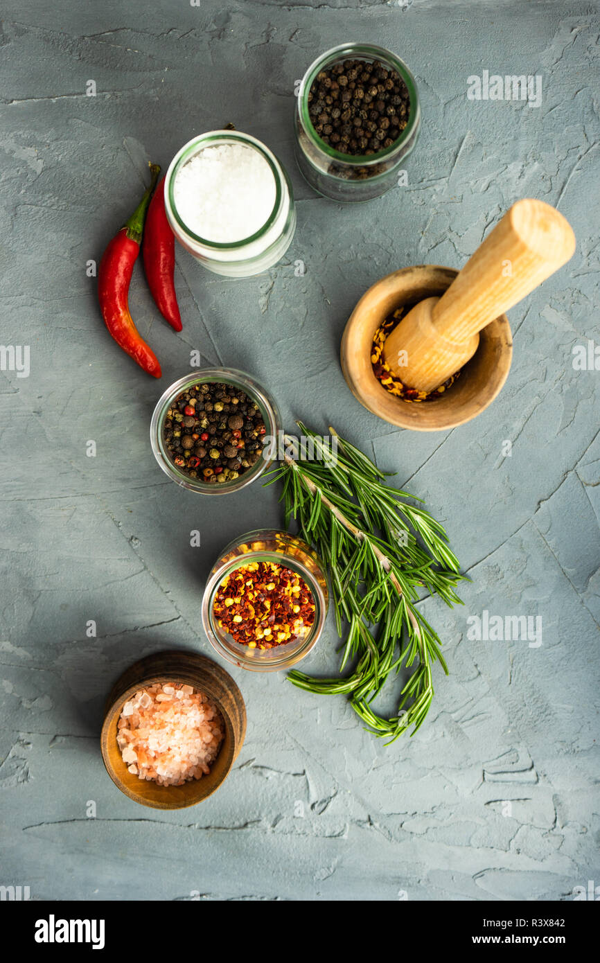 Organic spices like pepper, rosemary, different types of salt on rustic ...