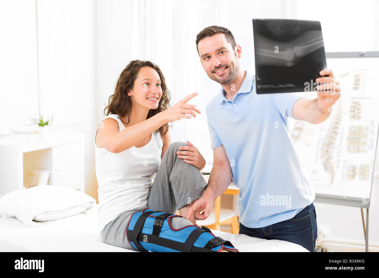 Young attractive physiotherapist analysing X-ray with patient Stock ...