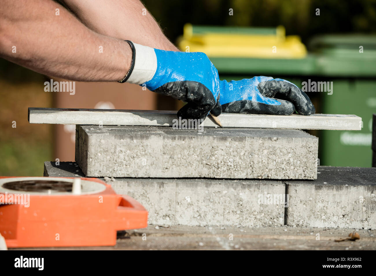 Builder marking a paving stone or block for cutting as he lays a new ...