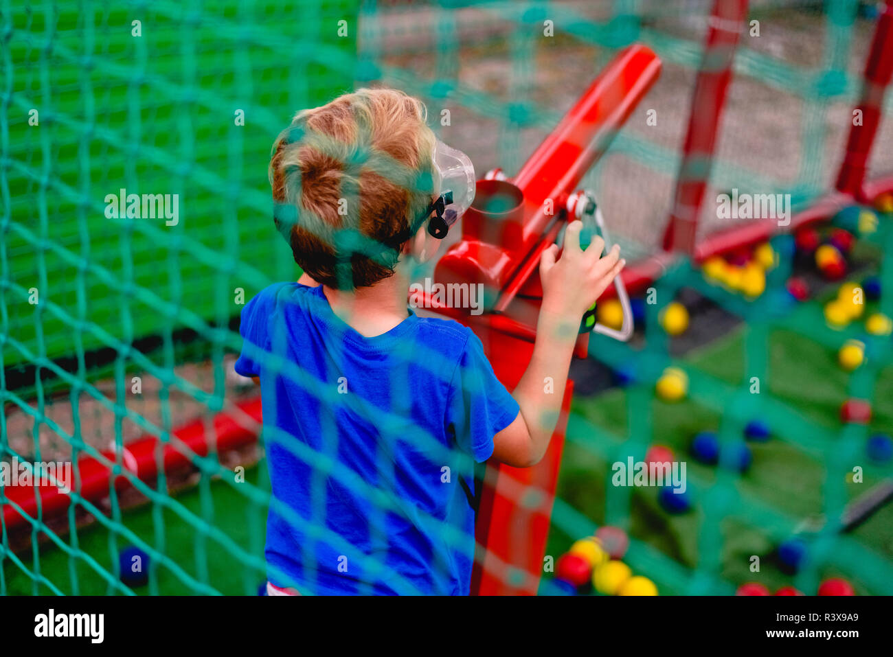 Child playing at a summer fair with a cannon of colored balls of ...