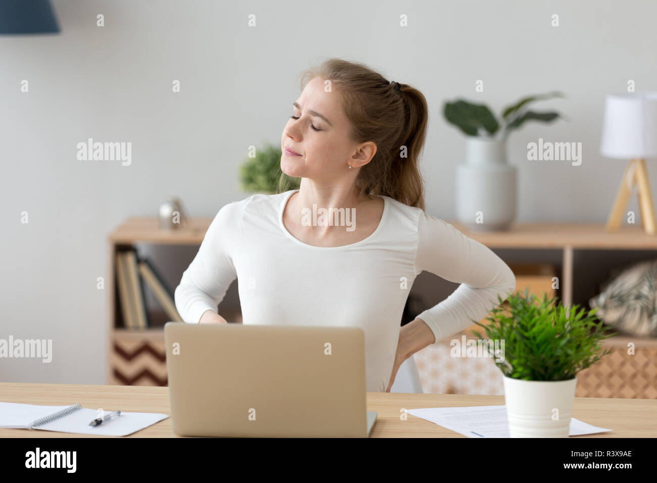 Tired girl stretching in chair suffering from back pain Stock Photo - Alamy