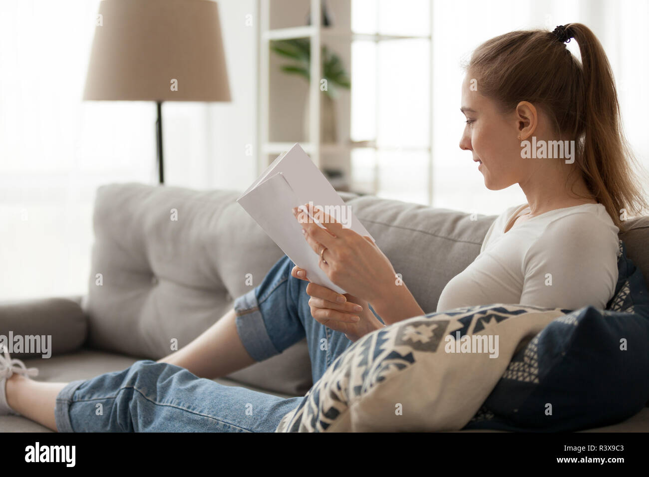 Girl relaxing at home reading book on sofa Stock Photo - Alamy