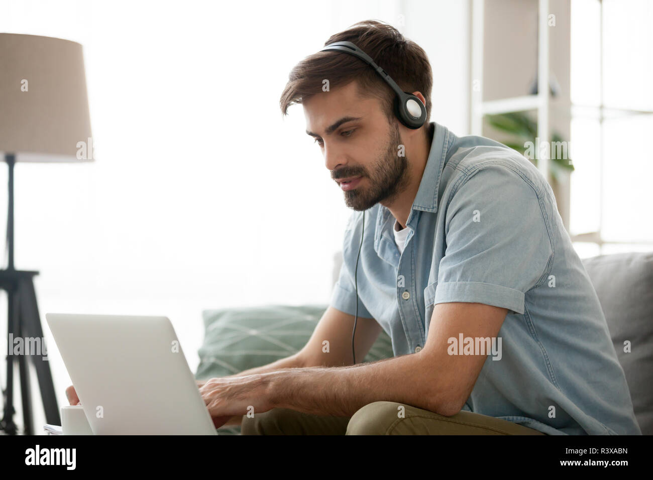 Focused millennial man in headset using computer online Stock Photo - Alamy