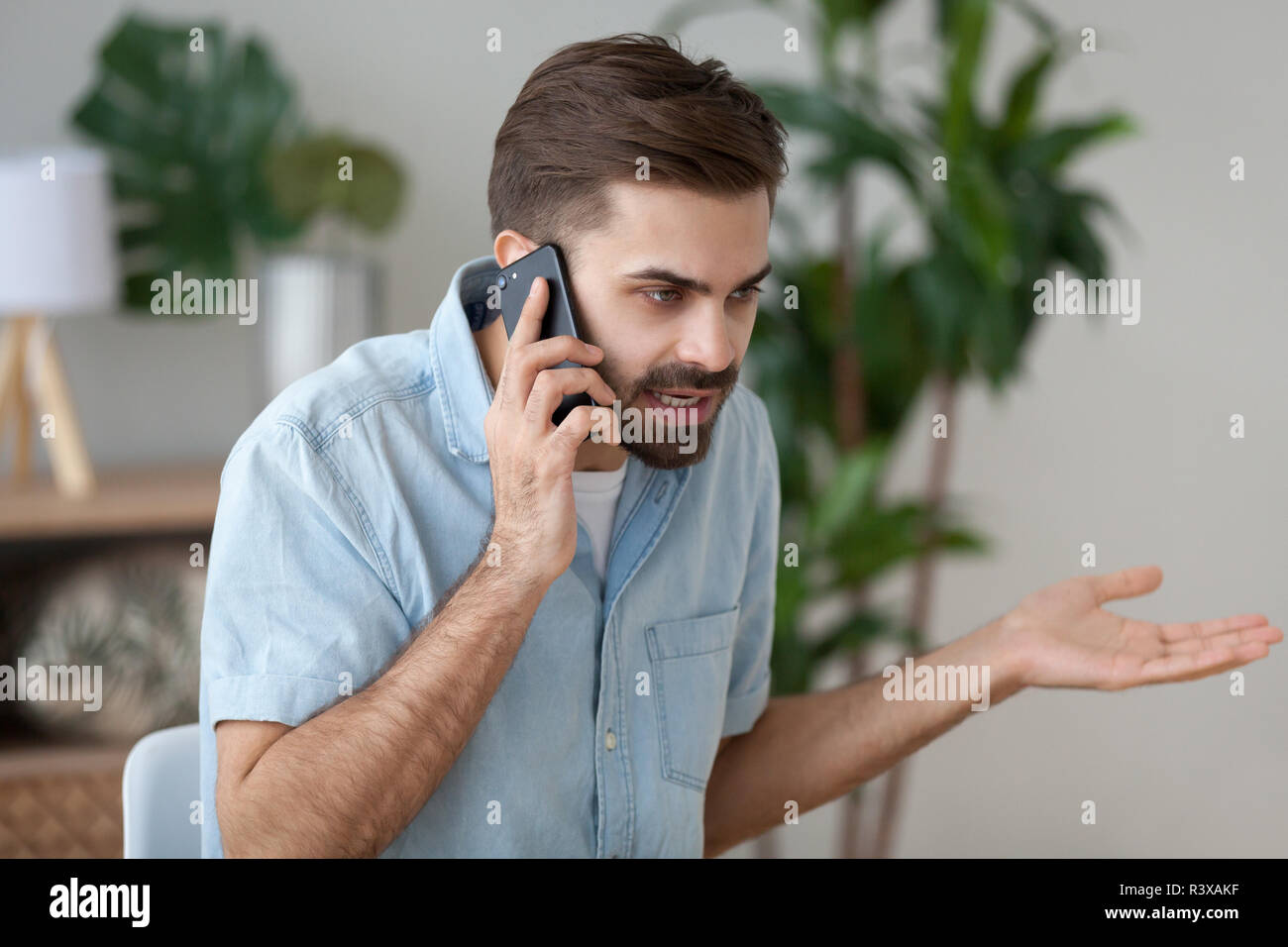 Angry man talking on smartphone solving work problem Stock Photo - Alamy