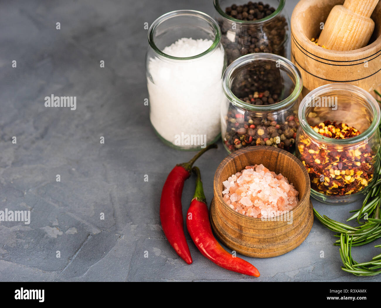 Organic spices like pepper, rosemary, different types of salt on rustic ...