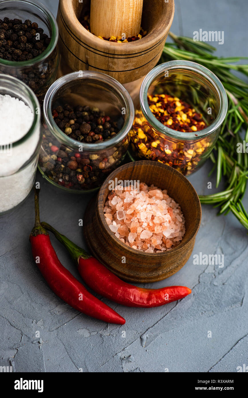 Organic spices like pepper, rosemary, different types of salt on rustic ...