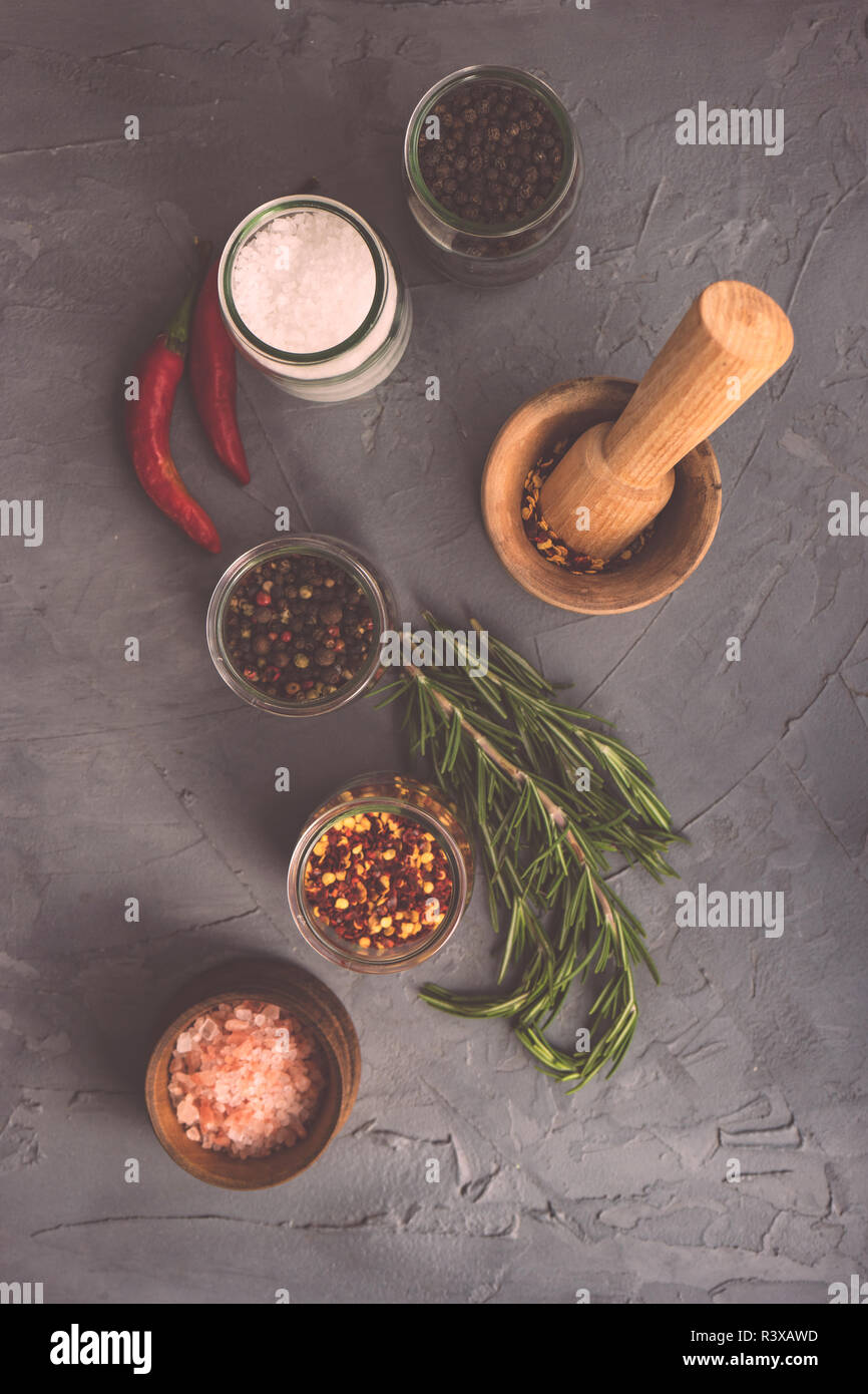 Organic spices like pepper, rosemary, different types of salt on rustic ...