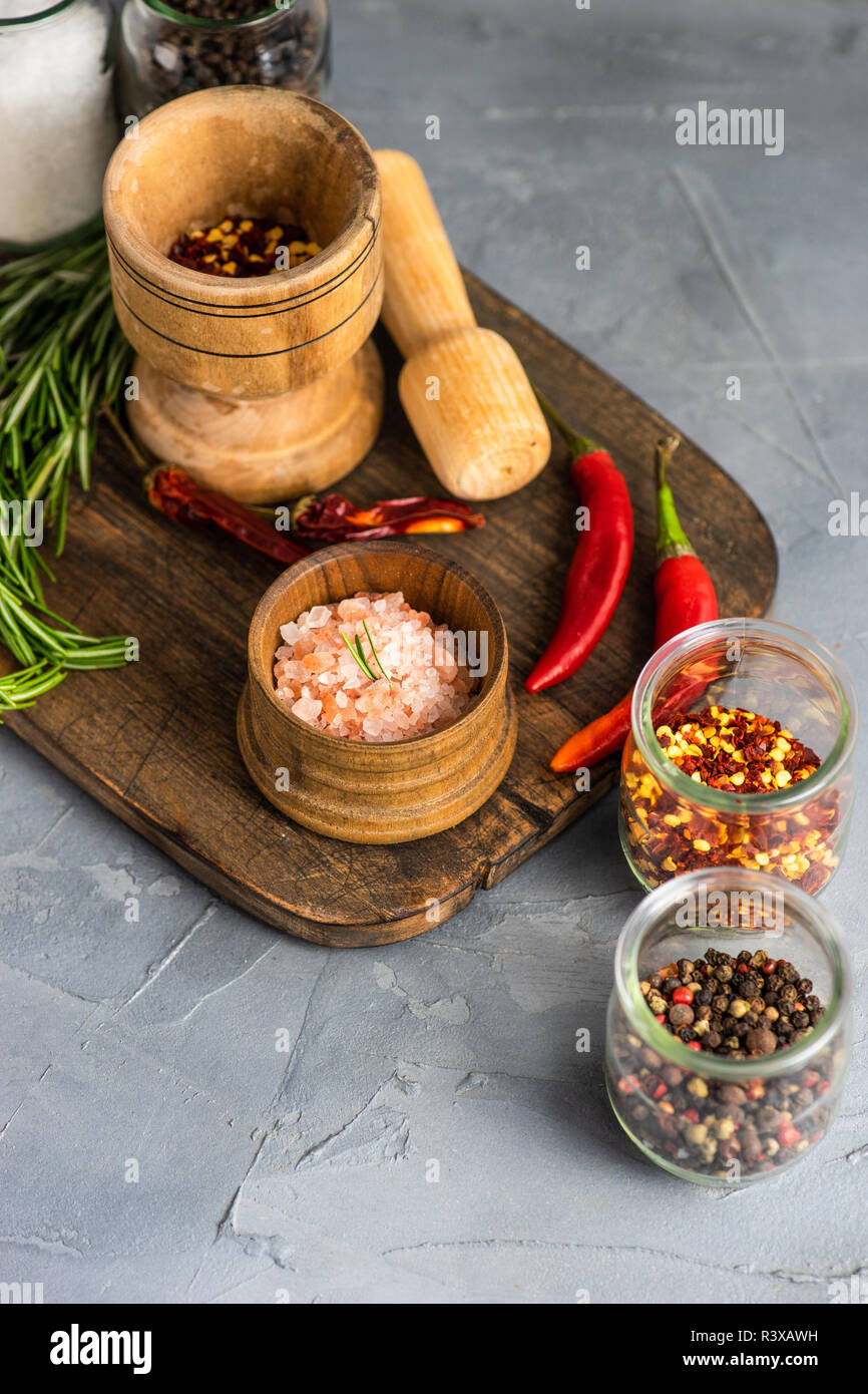Organic spices like pepper, rosemary, different types of salt on rustic ...