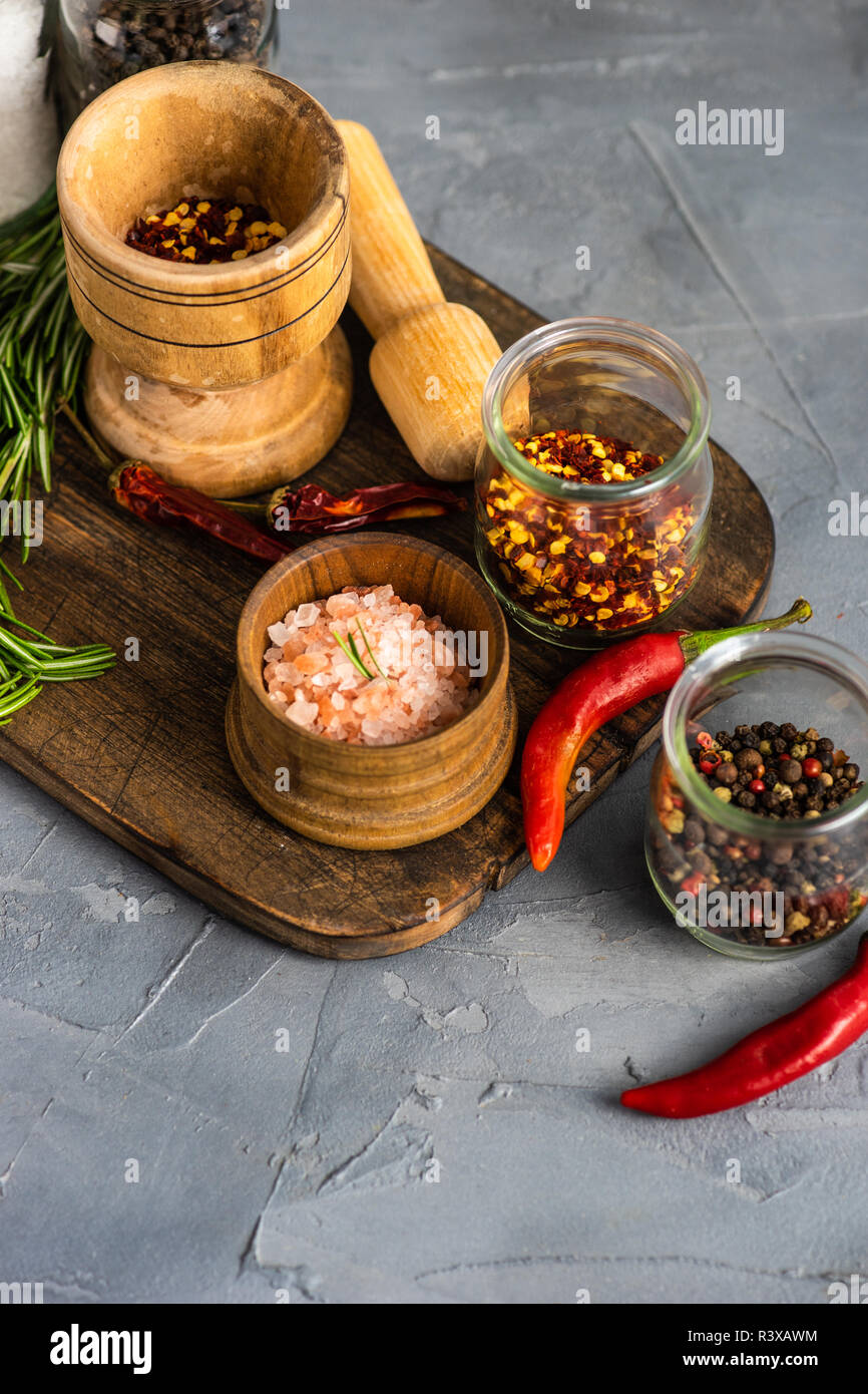 Organic spices like pepper, rosemary, different types of salt on rustic ...