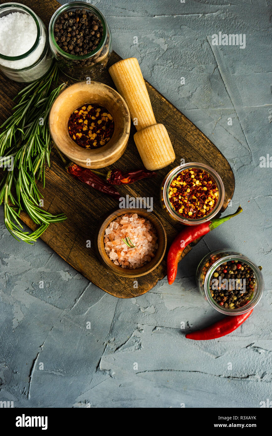 Organic spices like pepper, rosemary, different types of salt on rustic ...