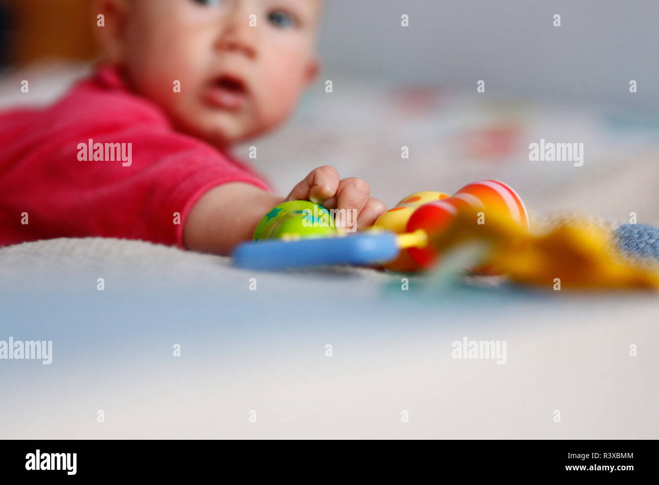 Adorable baby playing biting her rattle Stock Photo - Alamy