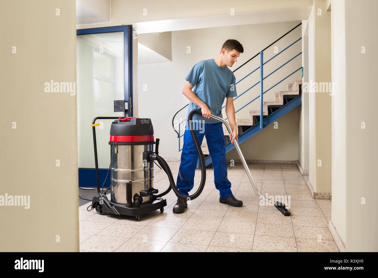 Male Worker Cleaning With Vacuum Cleaner Stock Photo - Alamy