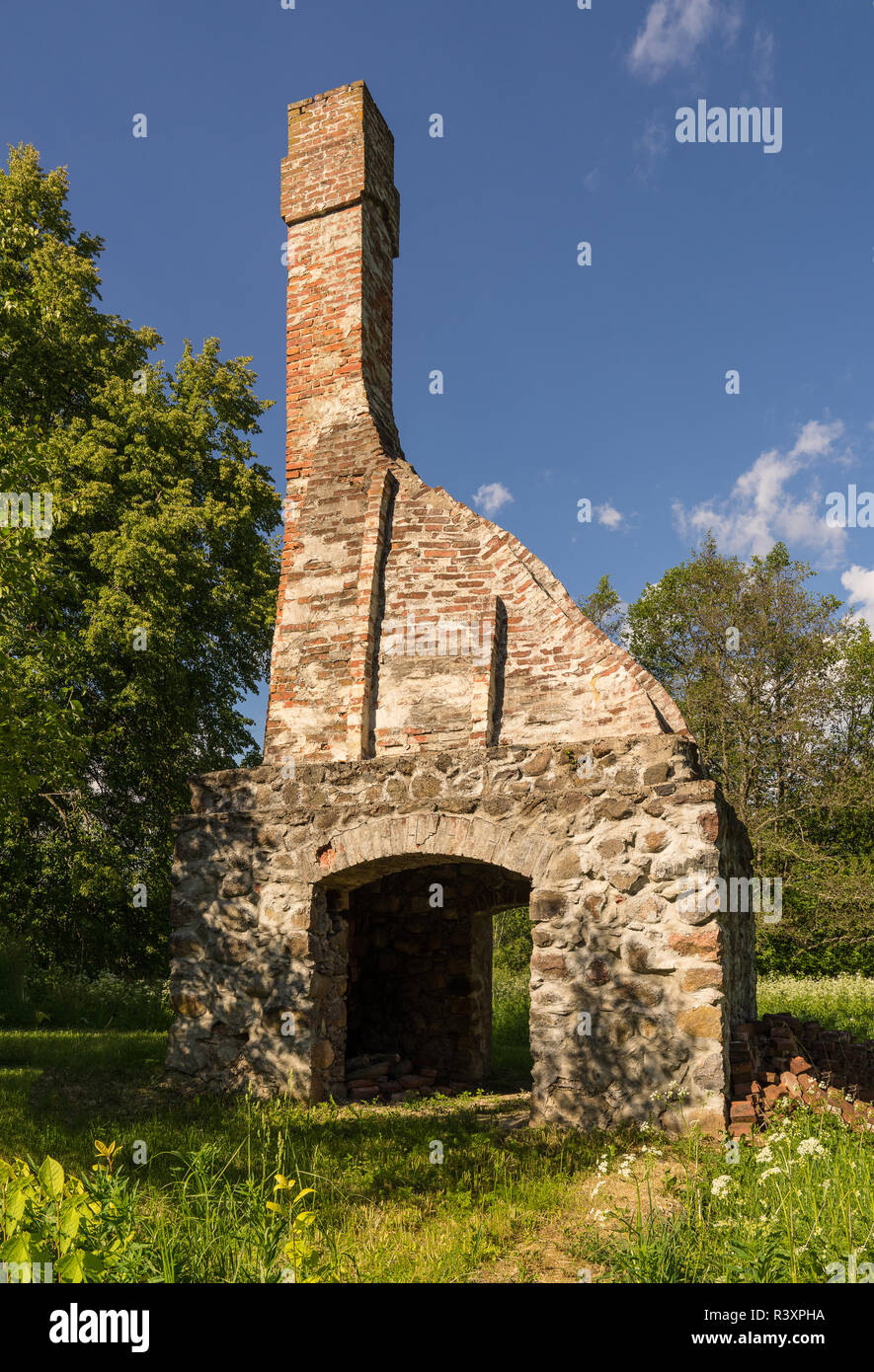 Abandoned ruin of oven chimney. Broken furnace. Green meadow ...