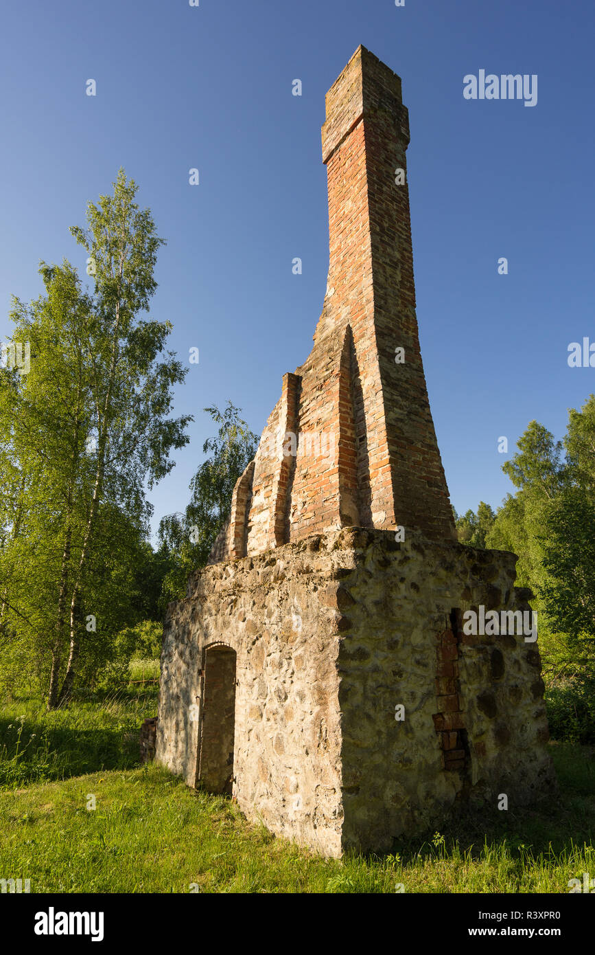 Abandoned ruin of oven chimney. Broken furnace. Green meadow ...