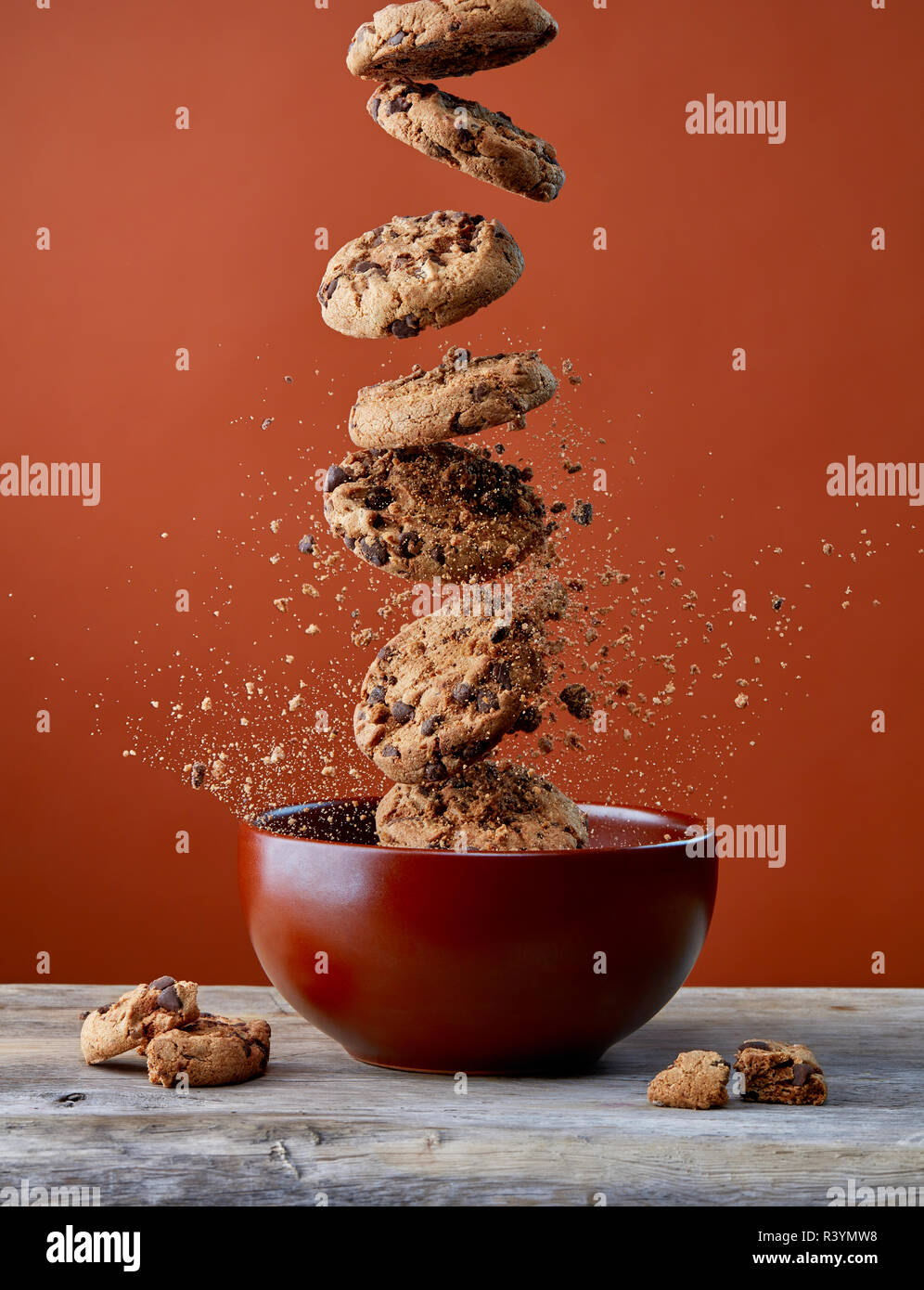 Chocolate chip cookies falling in clay bowl, brown background, food ...