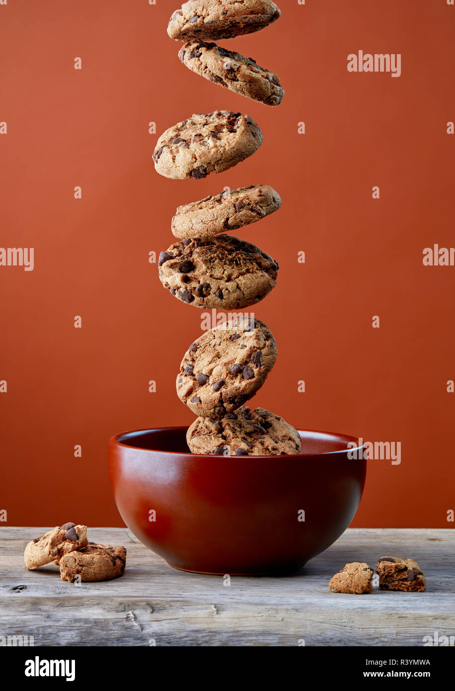 Chocolate chip cookies falling in clay bowl, brown background, food ...