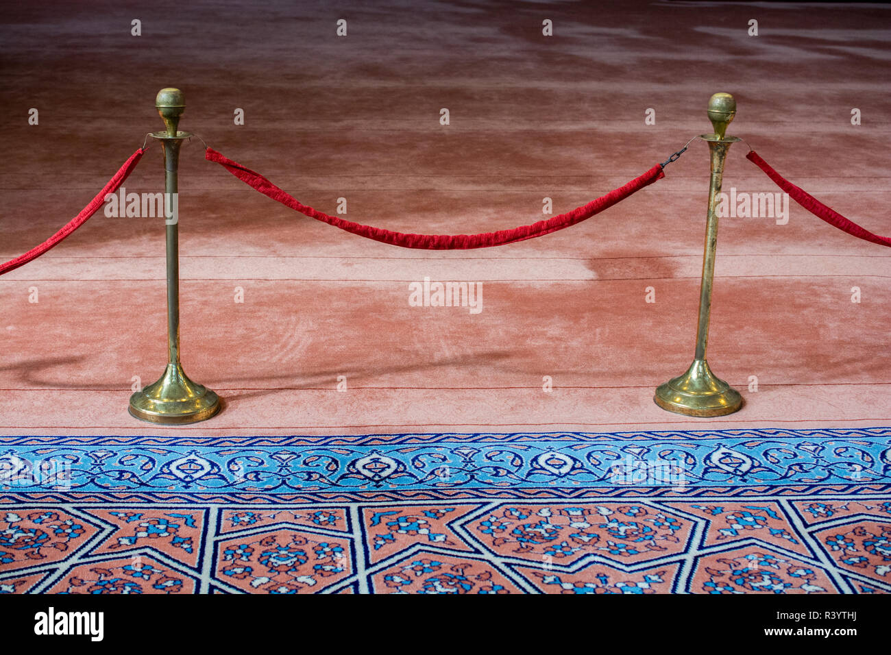 Velvet rope and metal stand near blue carpet in display Stock Photo - Alamy