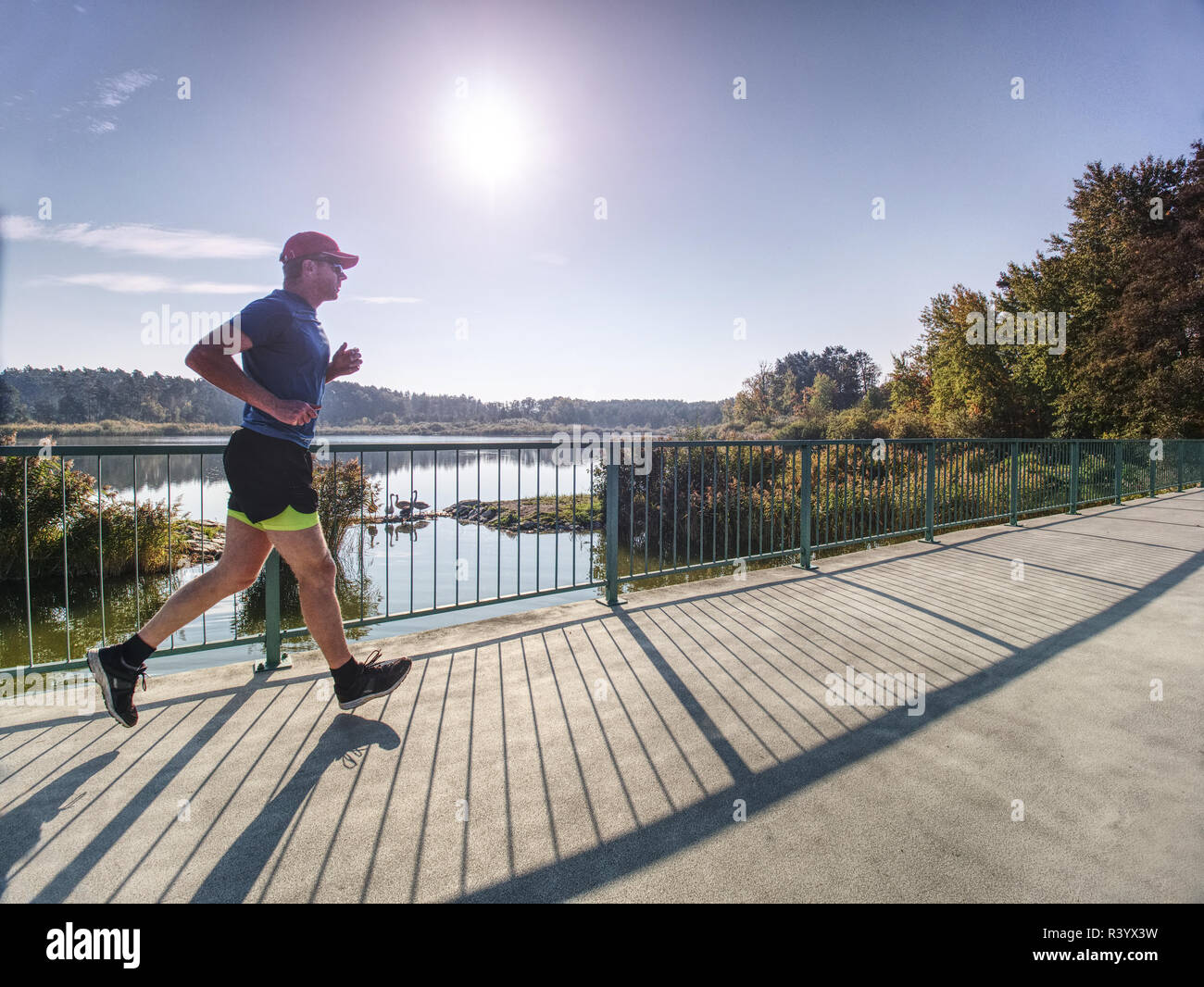 Full section view of fit slim man running on boardwalk. He is in sports ...