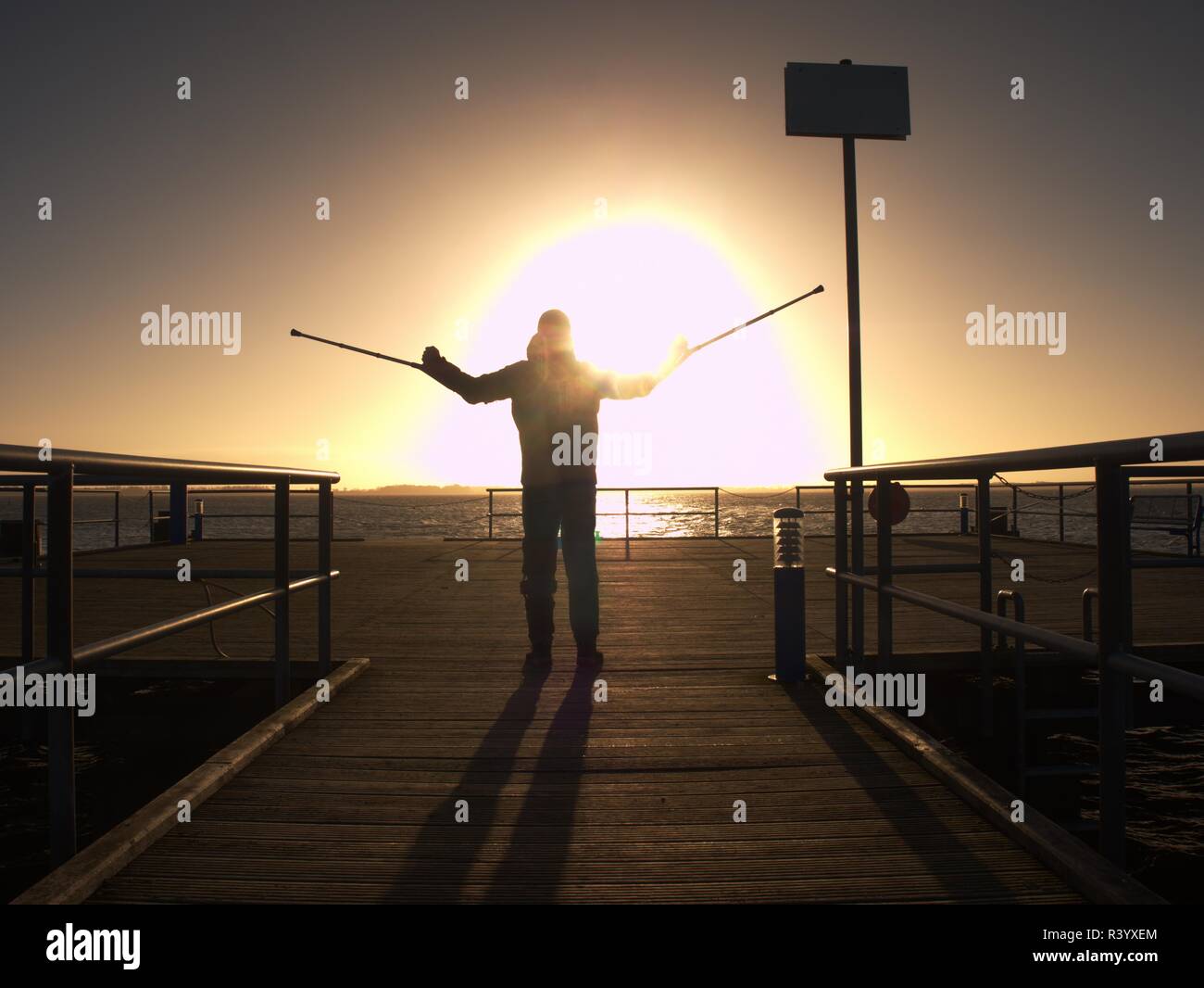Tourist with broken leg walk with crutches on beach bridge. Man is ...
