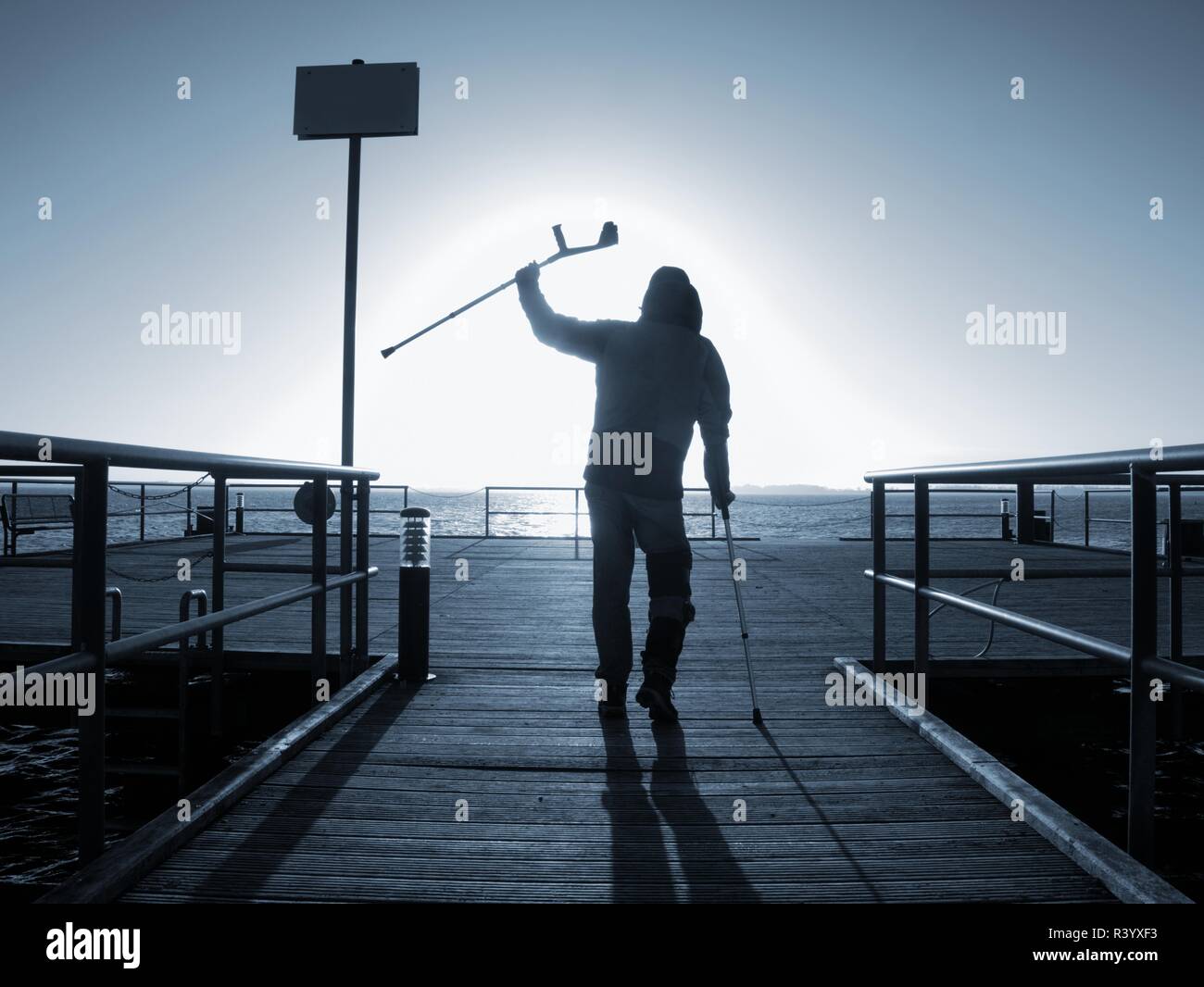 Tourist with broken leg walk with crutches on beach bridge. Man is ...