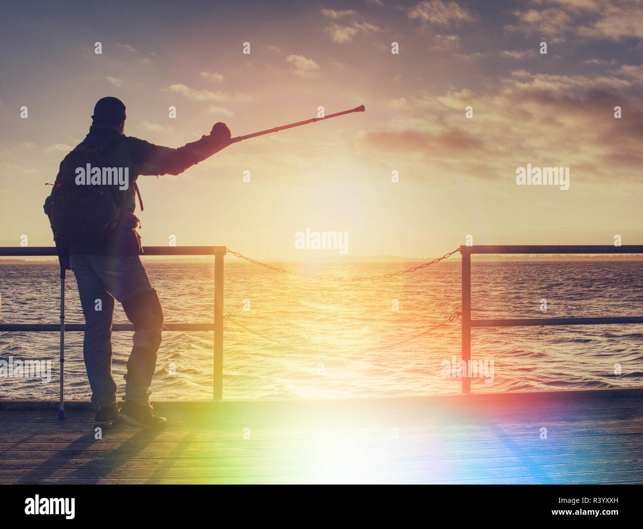 Man goes on the wooden pier in the sunrise. The wharf construction ...