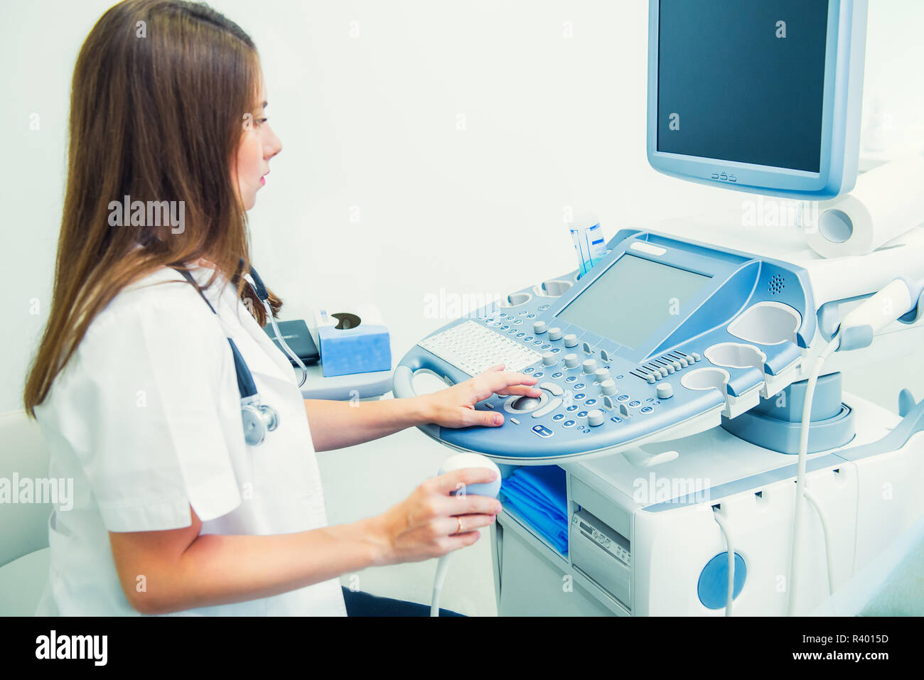 Serious, concentrated young doctor, specialist using Ultrasound ...