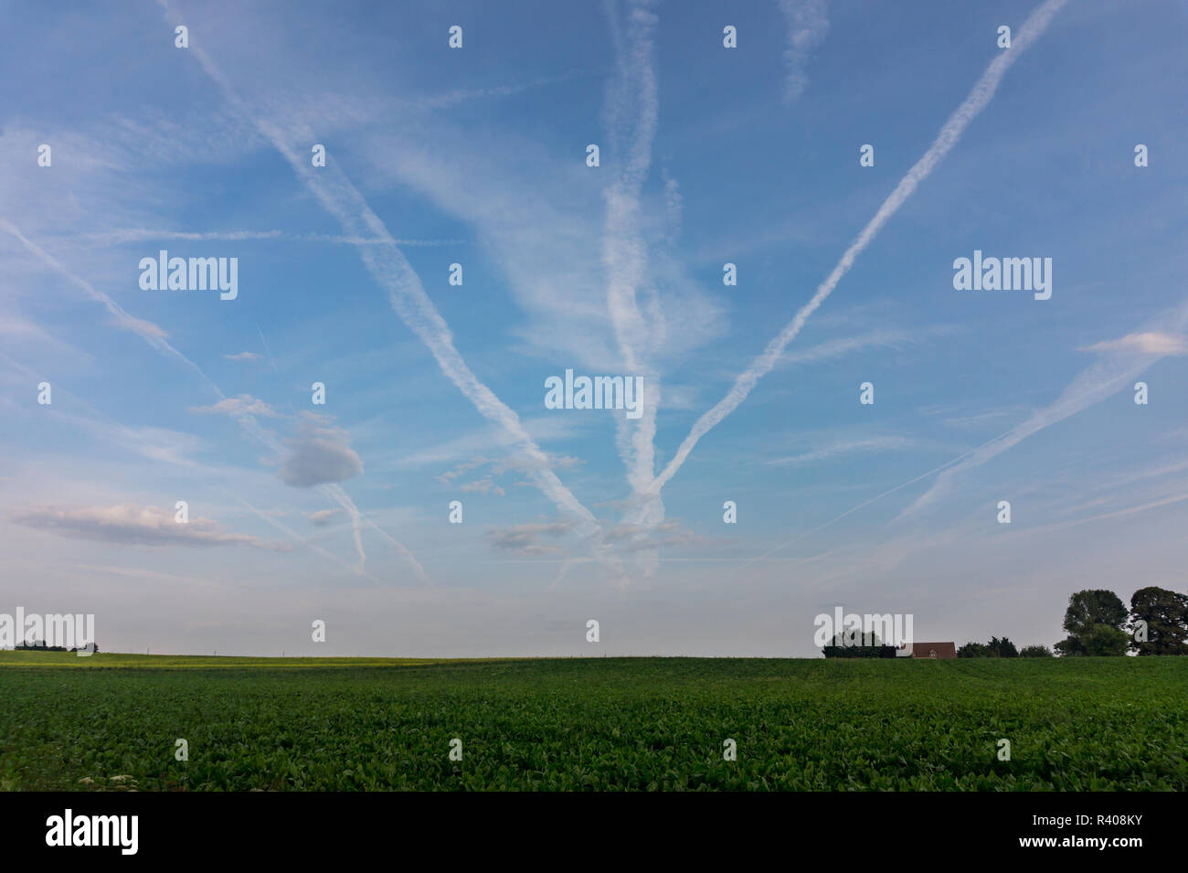 Inversion trails of aircraft in the sky above the green field Stock ...