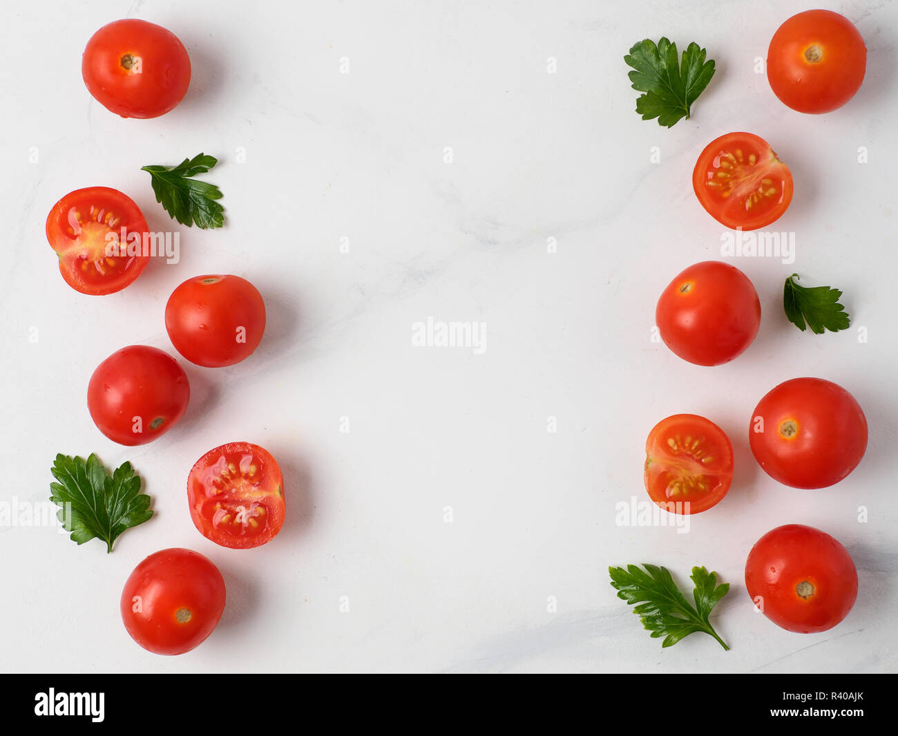Orange tomatoes on white marble table. Small red cherry tomatoes with ...