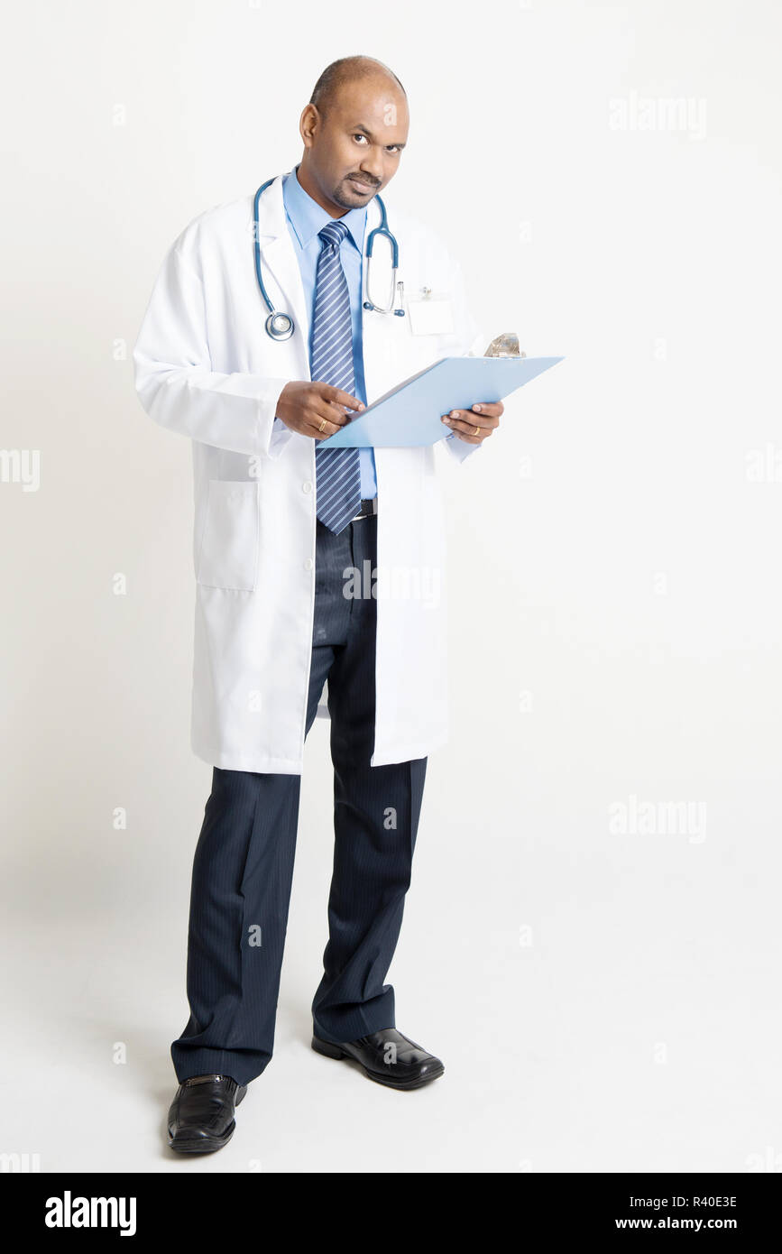 Mature Indian doctor reading medical report Stock Photo - Alamy