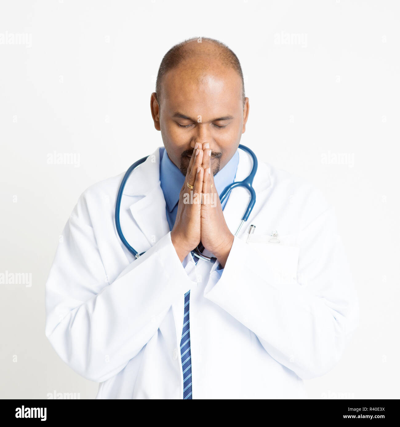 Mature Indian doctor praying Stock Photo - Alamy