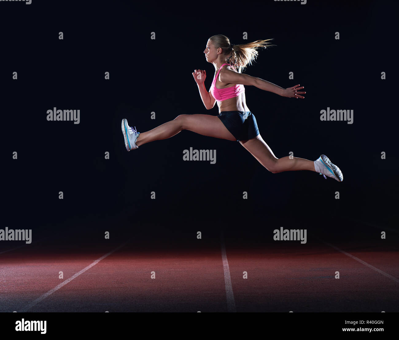 Athletic woman running on track Stock Photo - Alamy