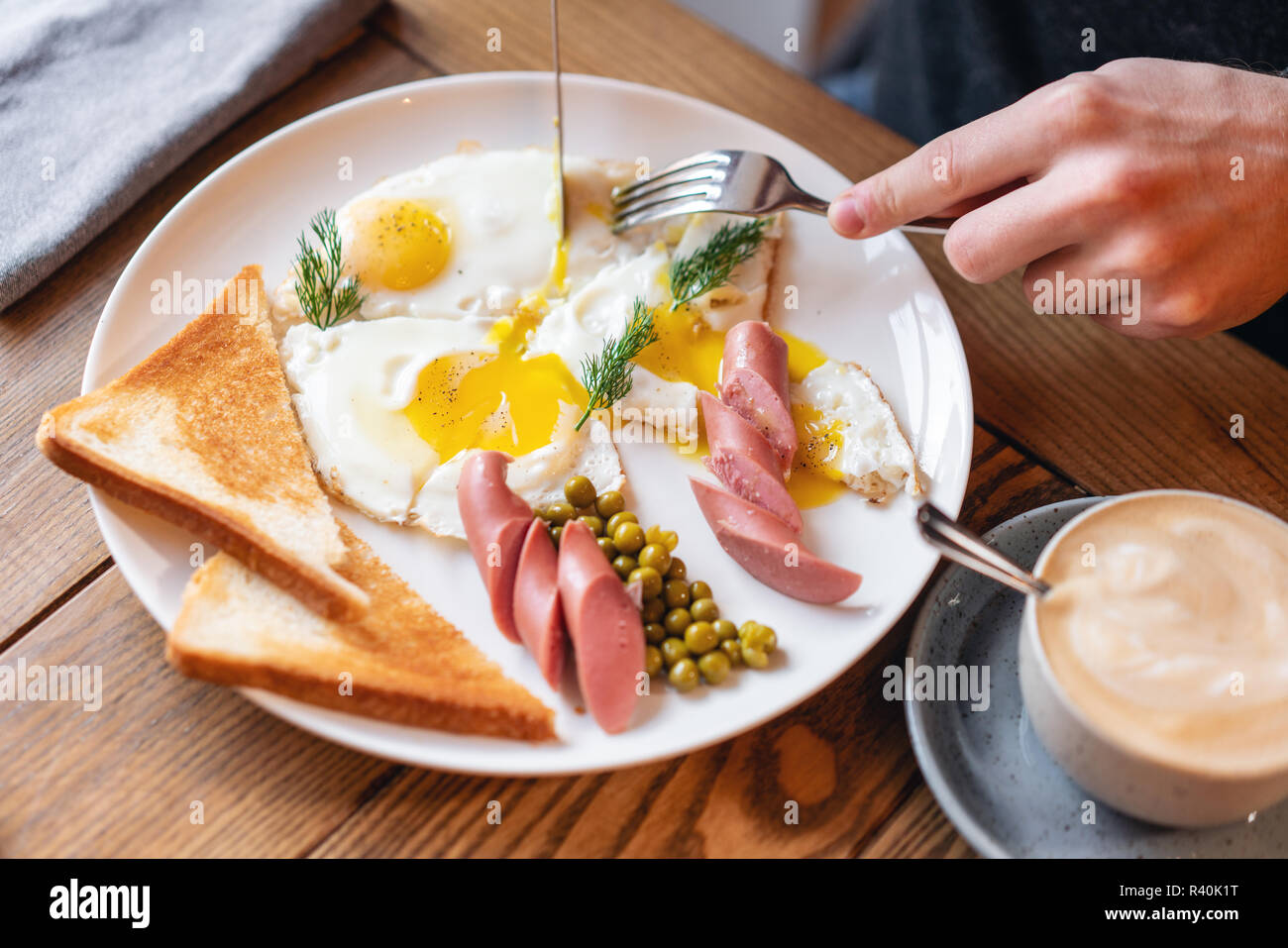 The man eat. Knife and fork in hand. Breakfast on the table.. American ...