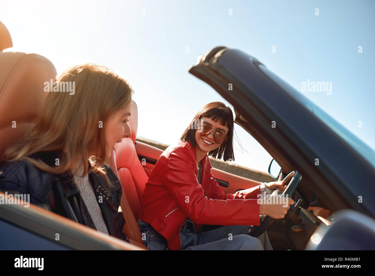 Two happy friends in the cabriolet driving everywhere and looking for ...