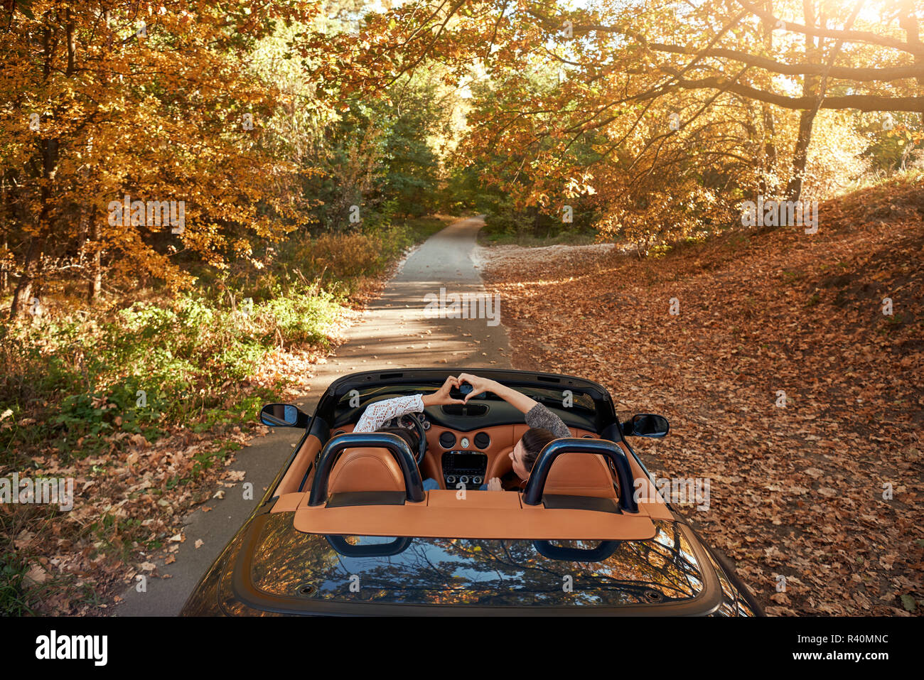 Female friends driving cabriolet with the hands up and having fun on ...