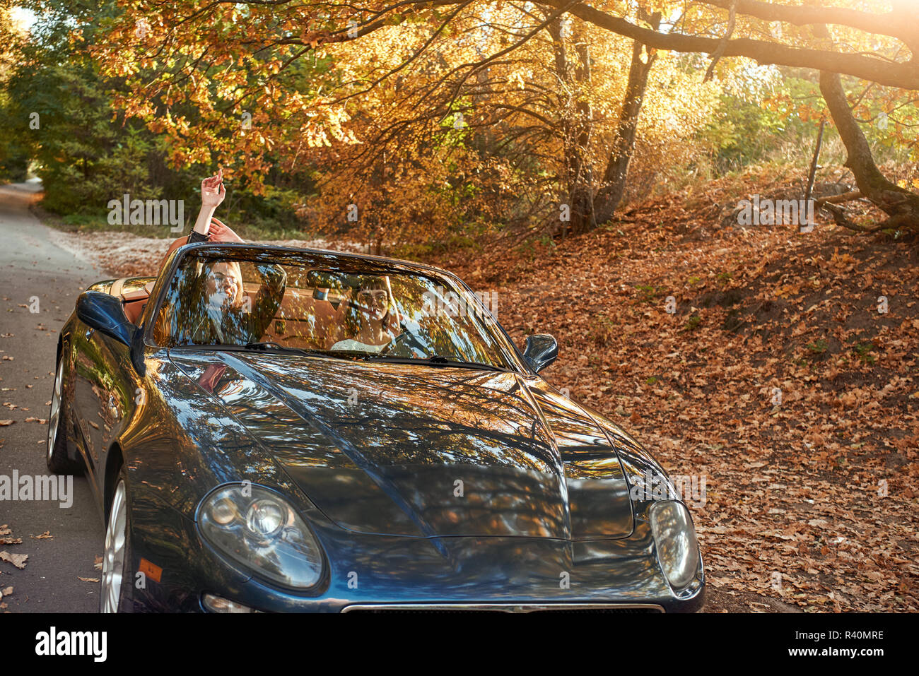 A black roofless car driving fast on the countryside asphalt road ...