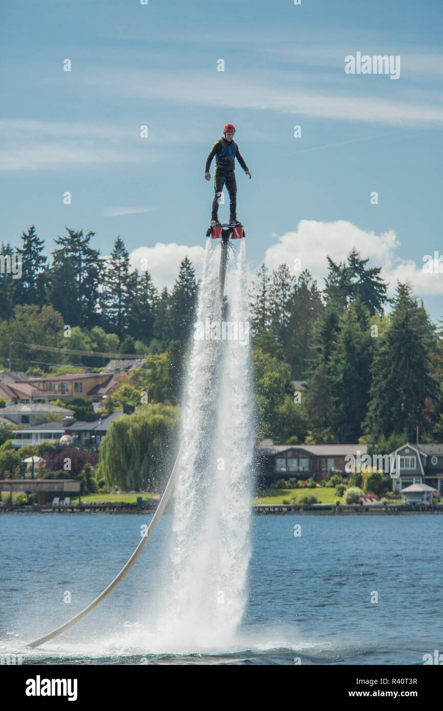 USA, Washington State, Kirkland, Man fly boarding on jets of water in ...