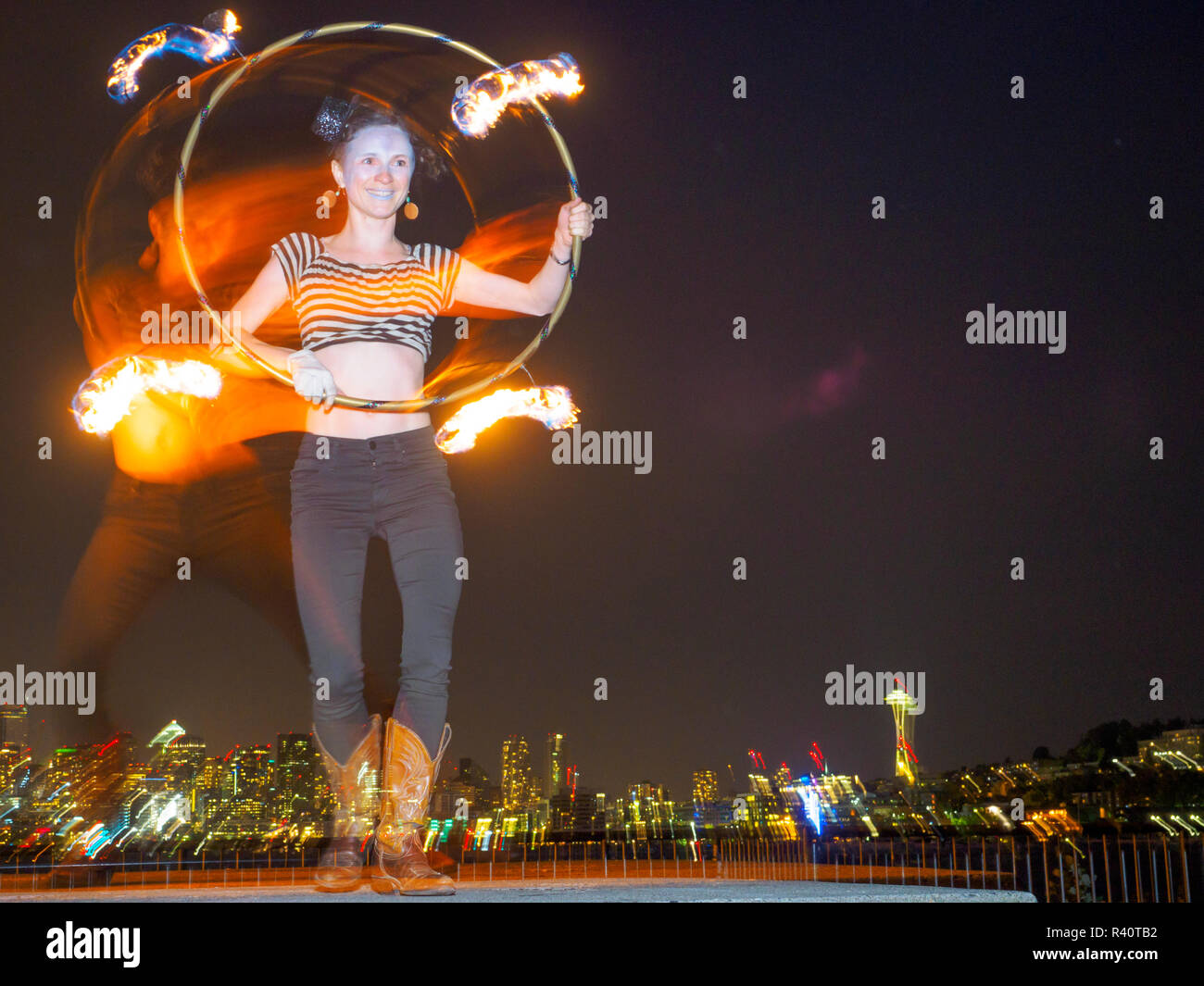 USA, Washington State, Seattle. Young woman juggling with fire in an ...