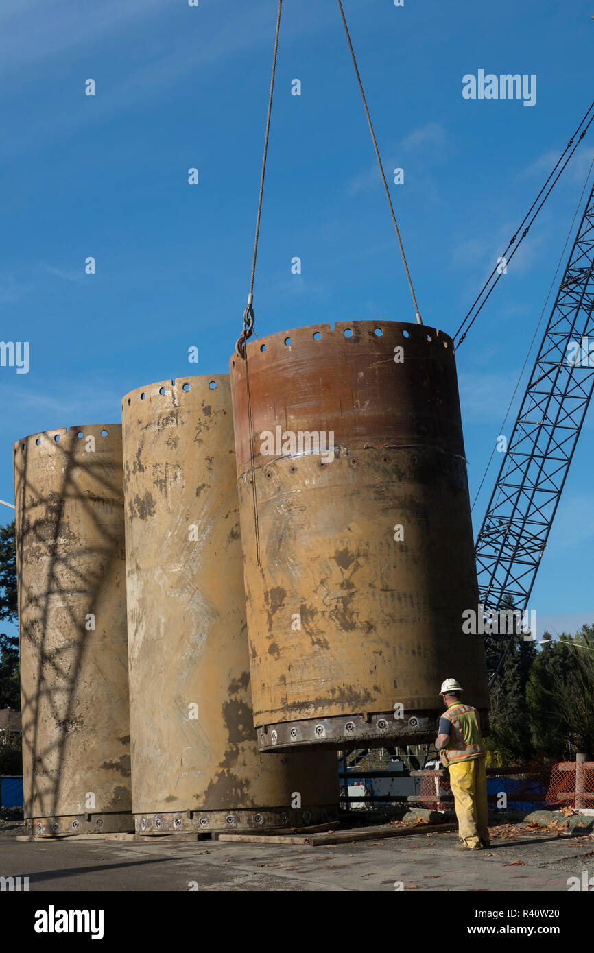 USA, Washington State, Bellevue. Crane lifting sections of pipe at ...