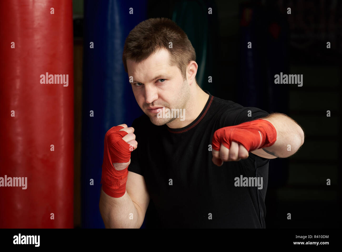 Portrait of kickboxing man holding fist up on modern gym background ...
