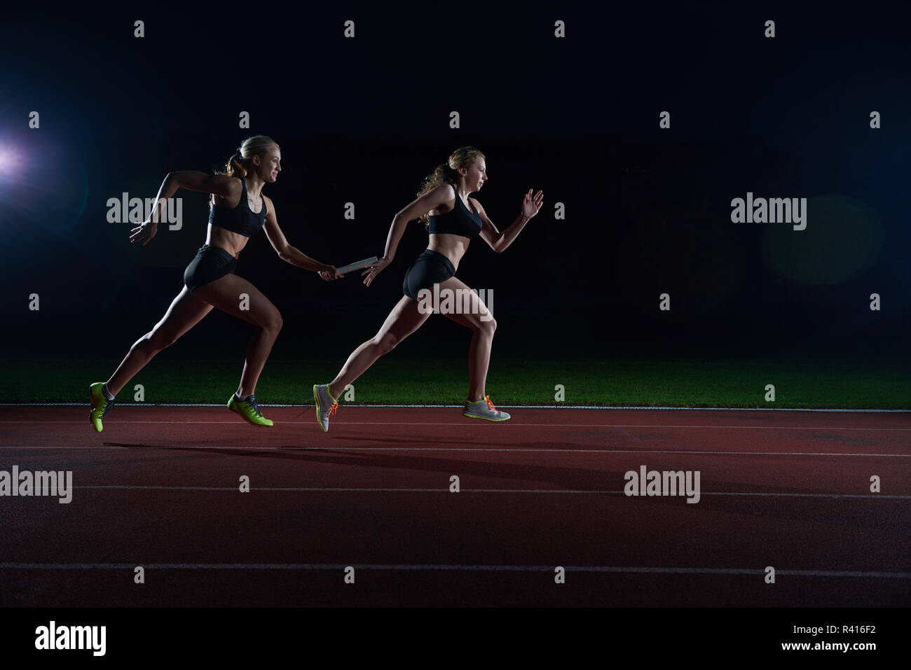 athletic runners passing baton in relay race Stock Photo - Alamy