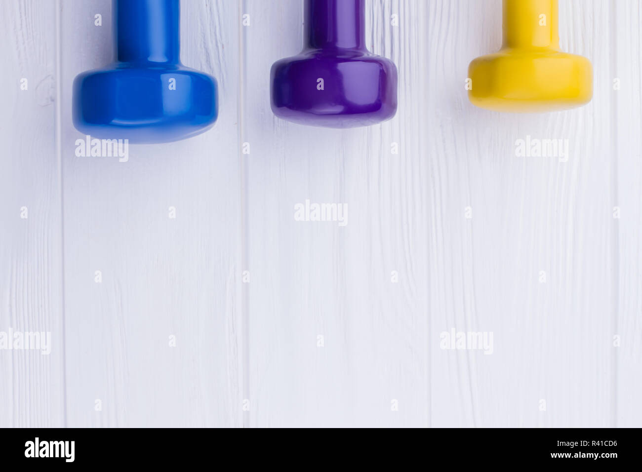 Border from colorful dumbbells on wooden background. Three different ...