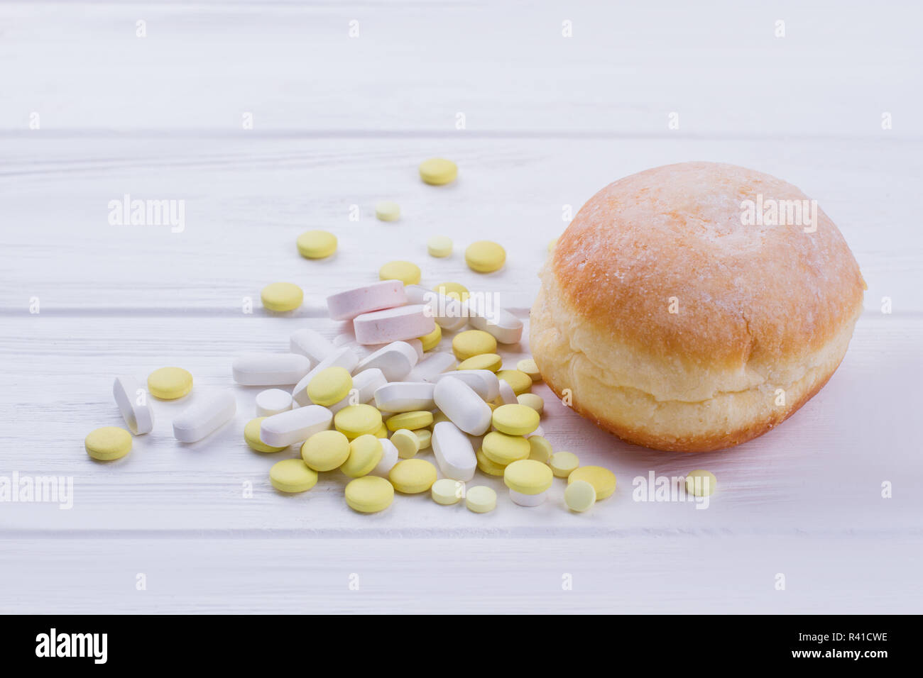Donut and pills on wooden background. Unhealthy food and medical pills ...